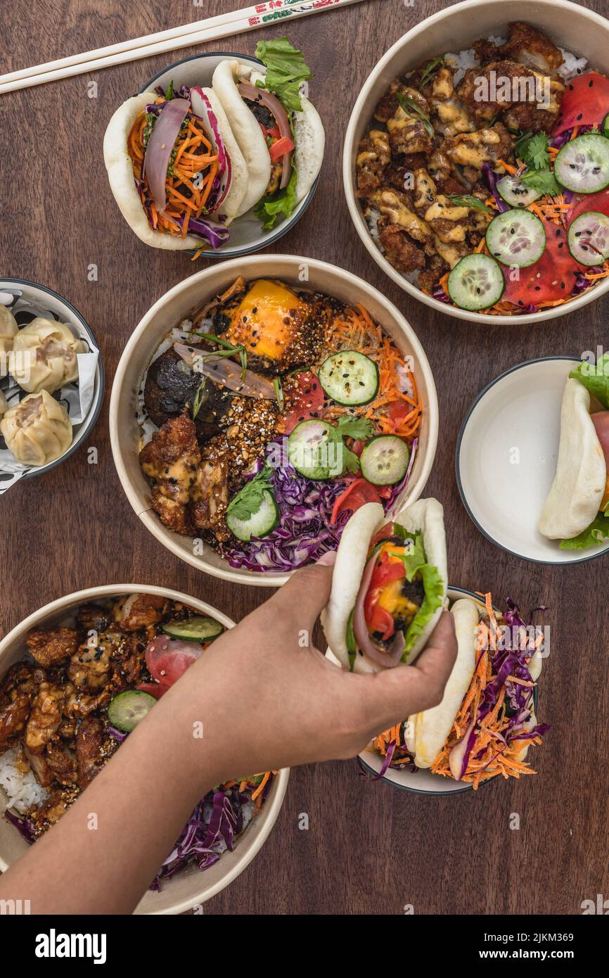 A top view shot of a table with Asian street food, poke bowl, bao, bun ...
