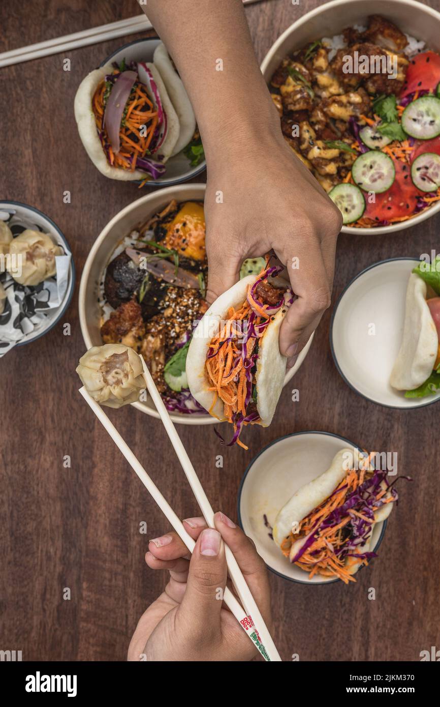 A top view shot of a table with Asian street food, poke bowl, bao, bun ...