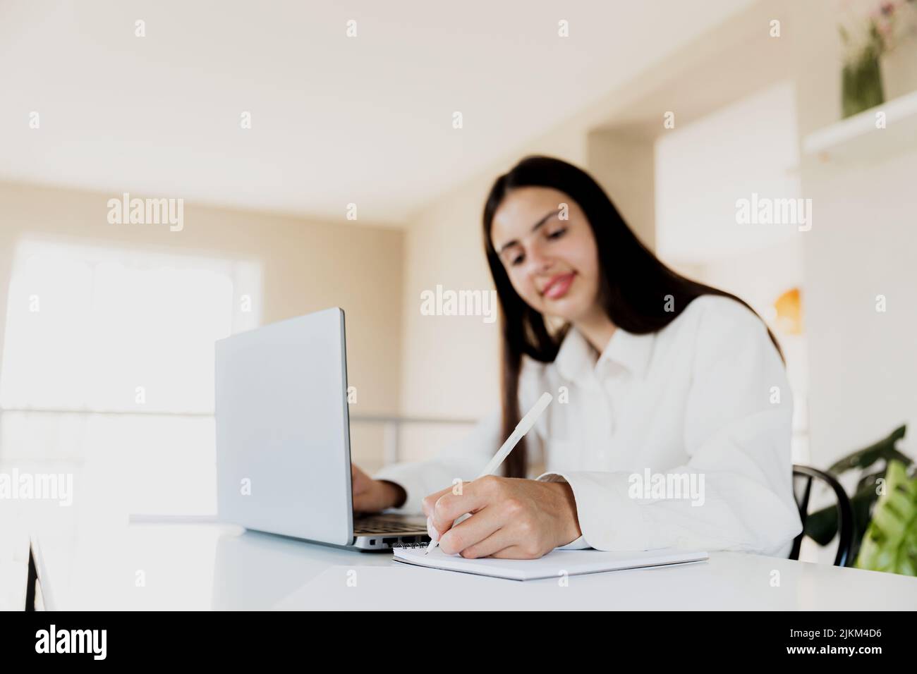 Caucasian business woman sitting at desk, reading from computer, taking ...