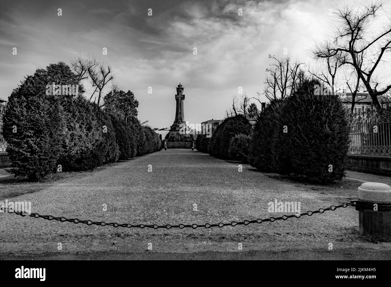 A grayscale shot of a way to the monument with a cross and sculptures ...
