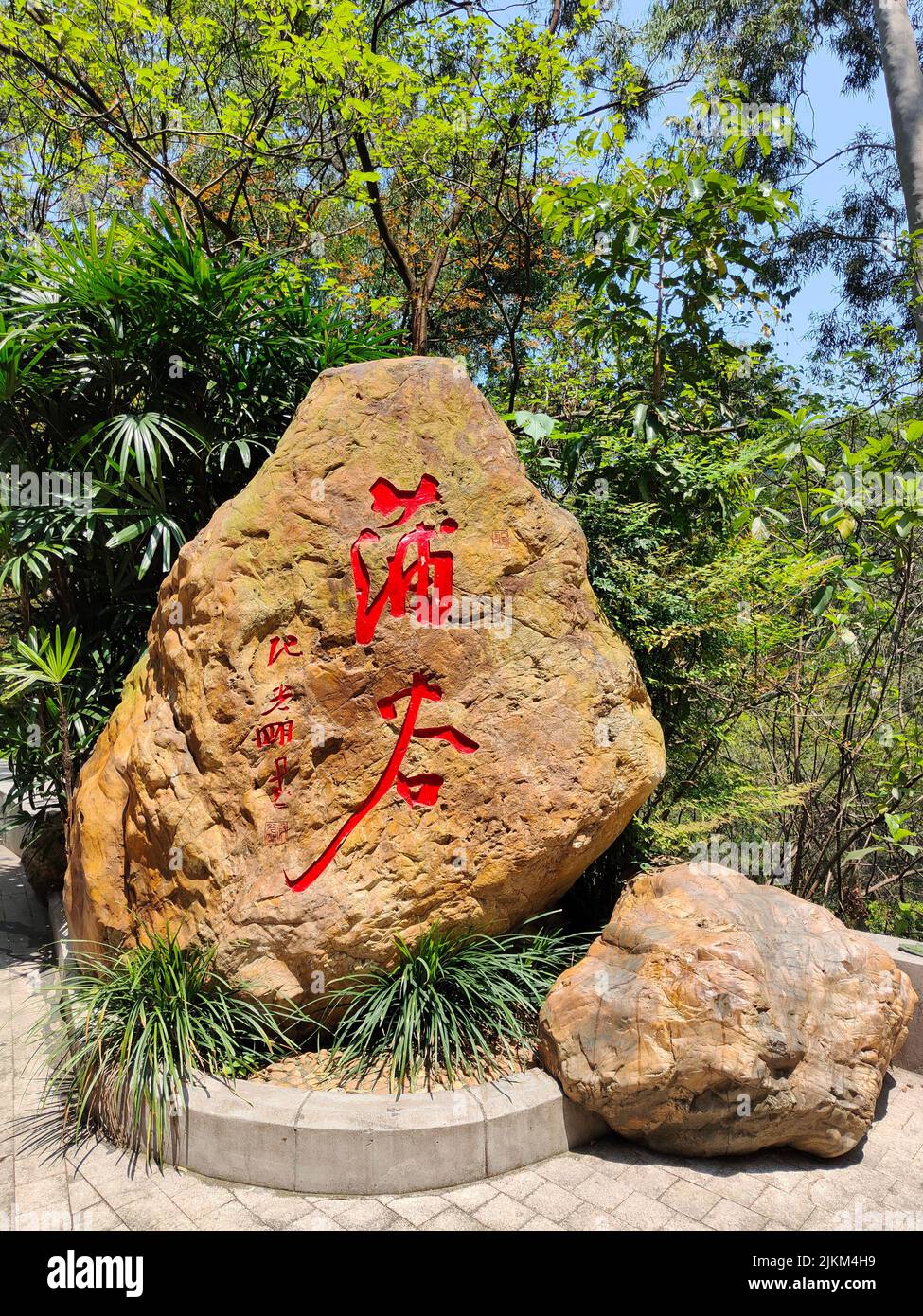 A vertical shot of a big boulder with Chinese writing on it at the ...