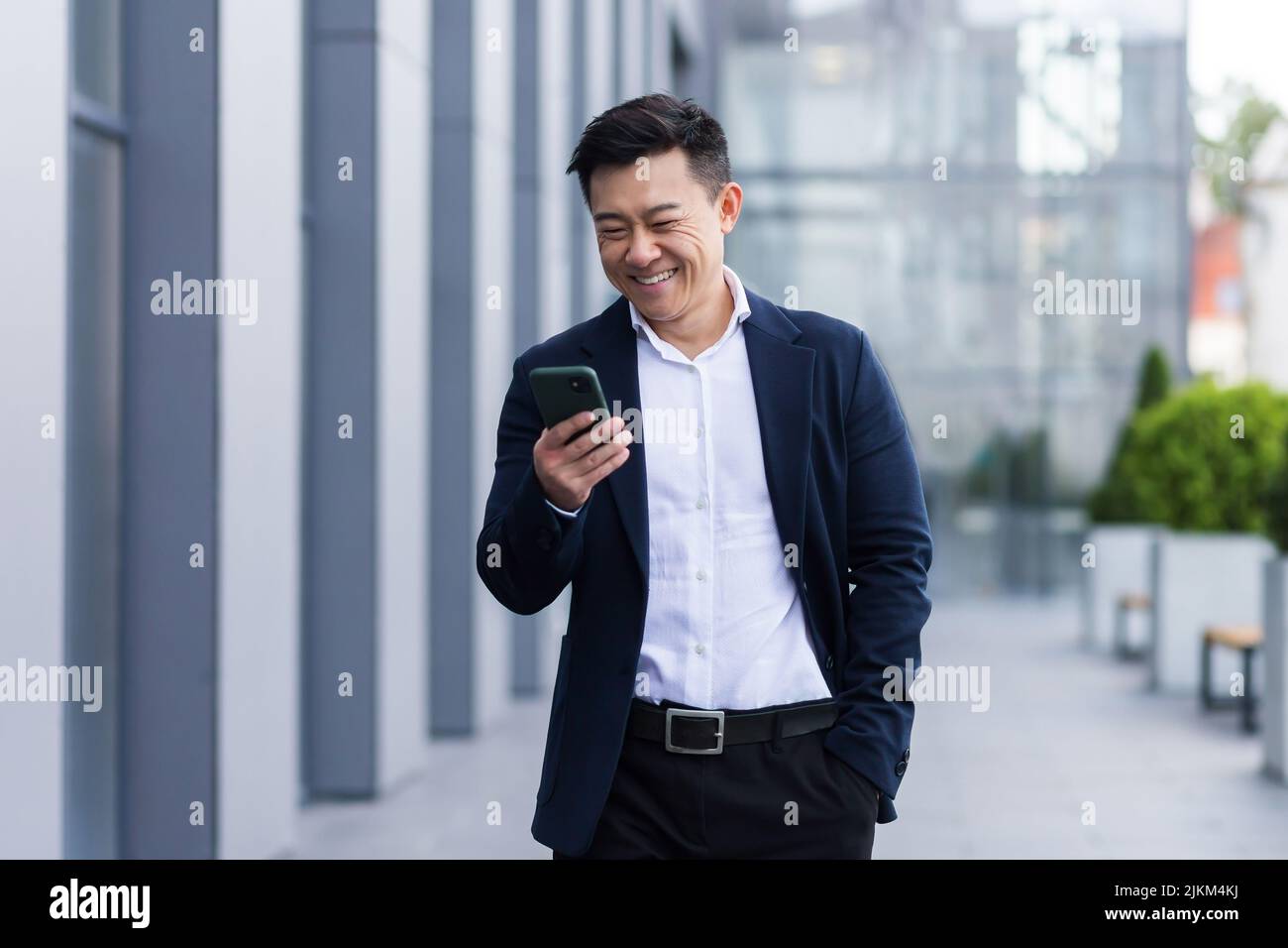 asian male freelancer walking near business center holding phone ...
