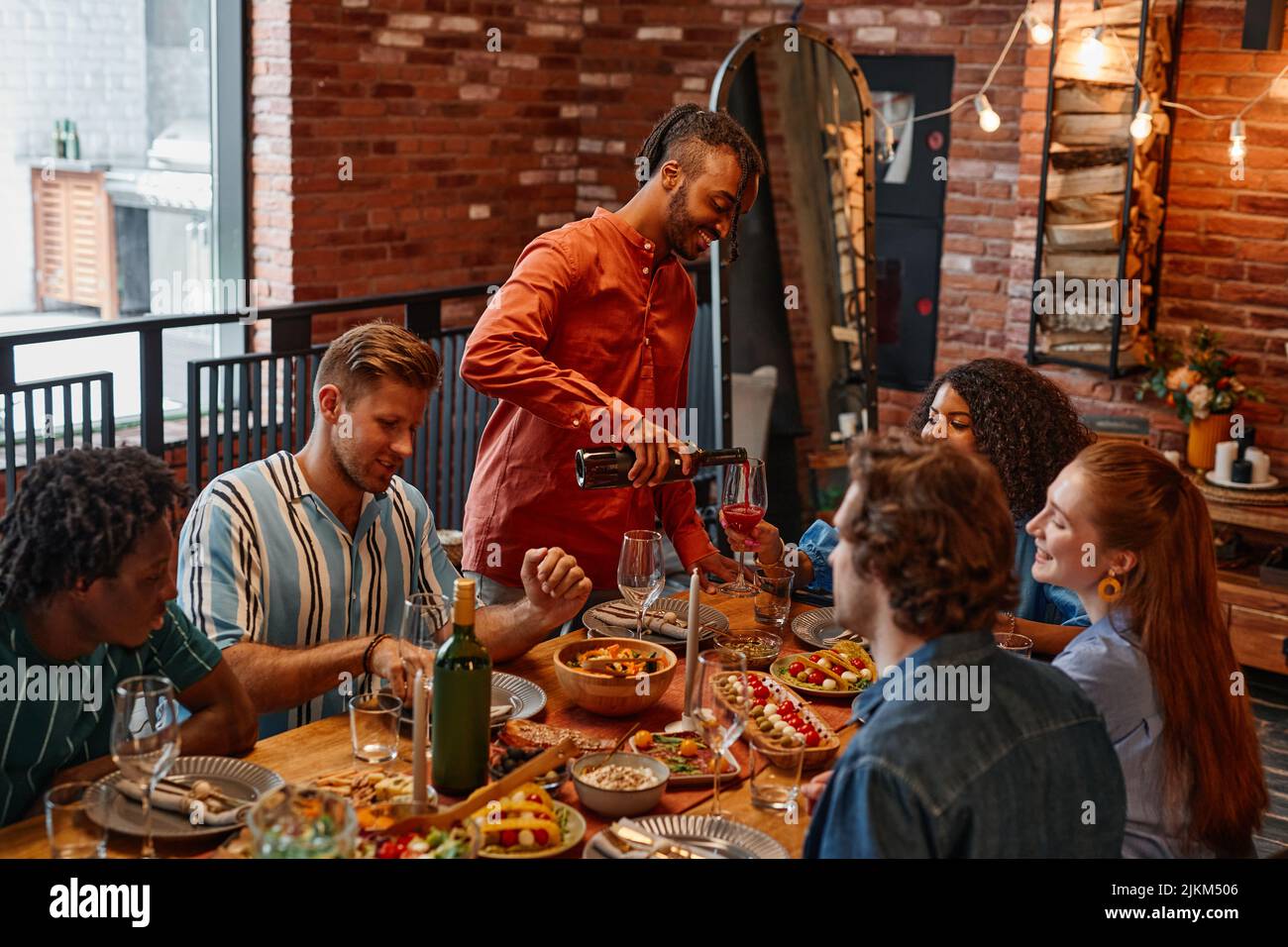 Warm toned shot of diverse group of friends enjoying dinner party in ...