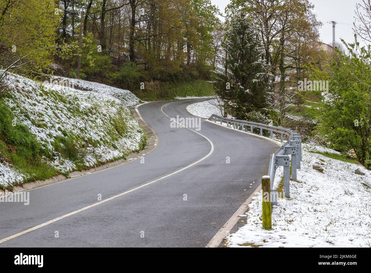 An asphalt road passing through a forested area covered with snow Stock Photo - Alamy