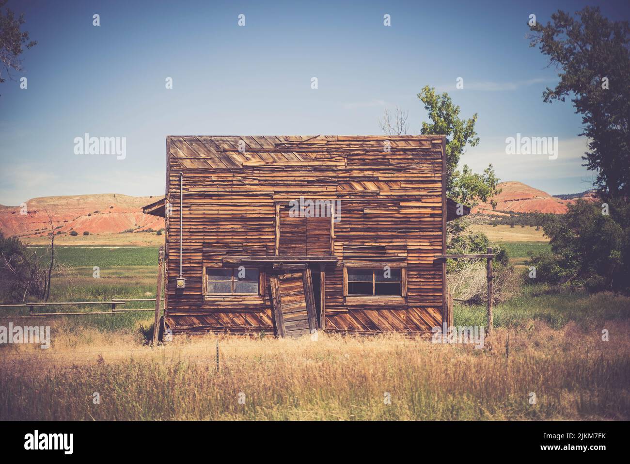 An old wooden hut with a broken door isolated in the field under the ...