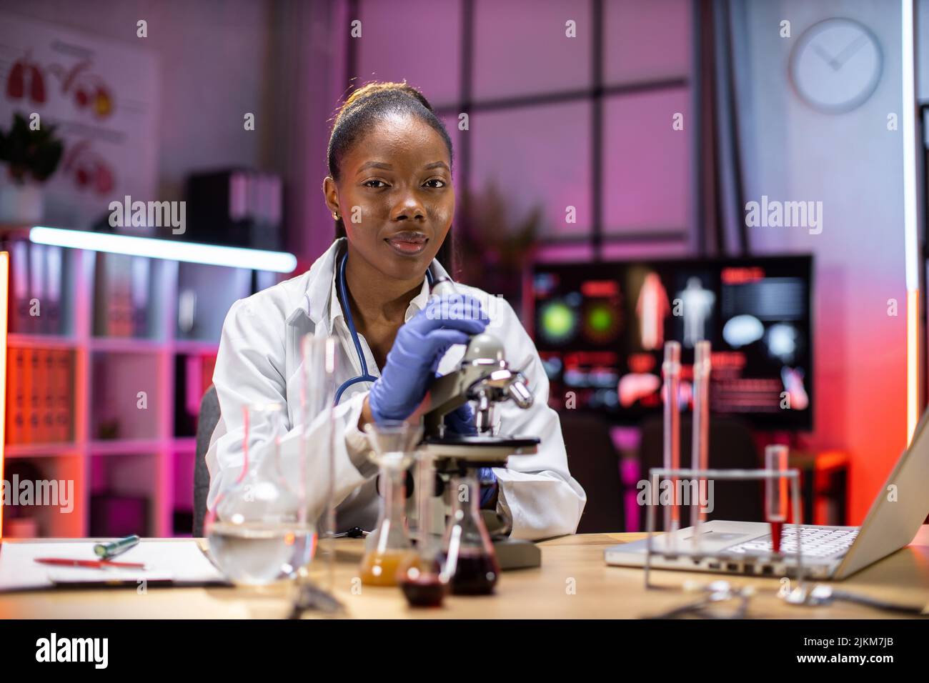 Modern medical research laboratory: portrait of african scientist working, using microscope ...