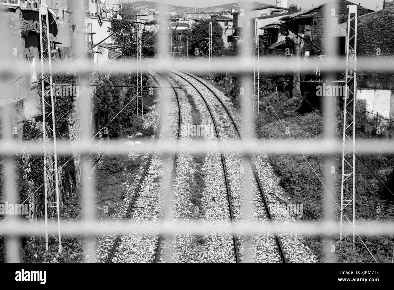 A black and white shot of train railways behind metal bars Stock Photo ...