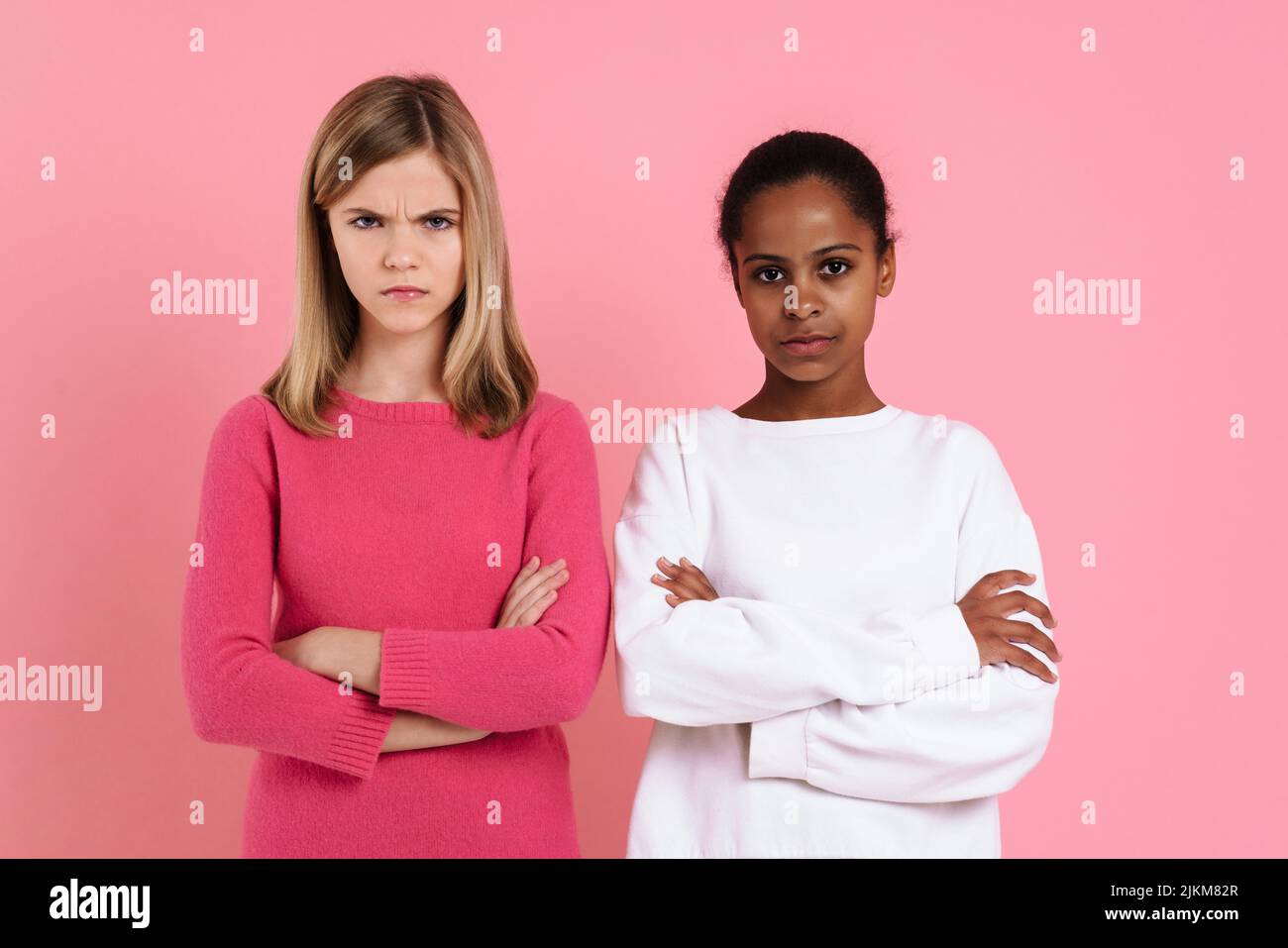 Multiracial girls frowning while posing with arms crossed isolated over ...