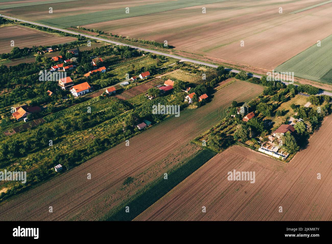 Rural landscape with houses and cultivated fields on sunny spring day ...