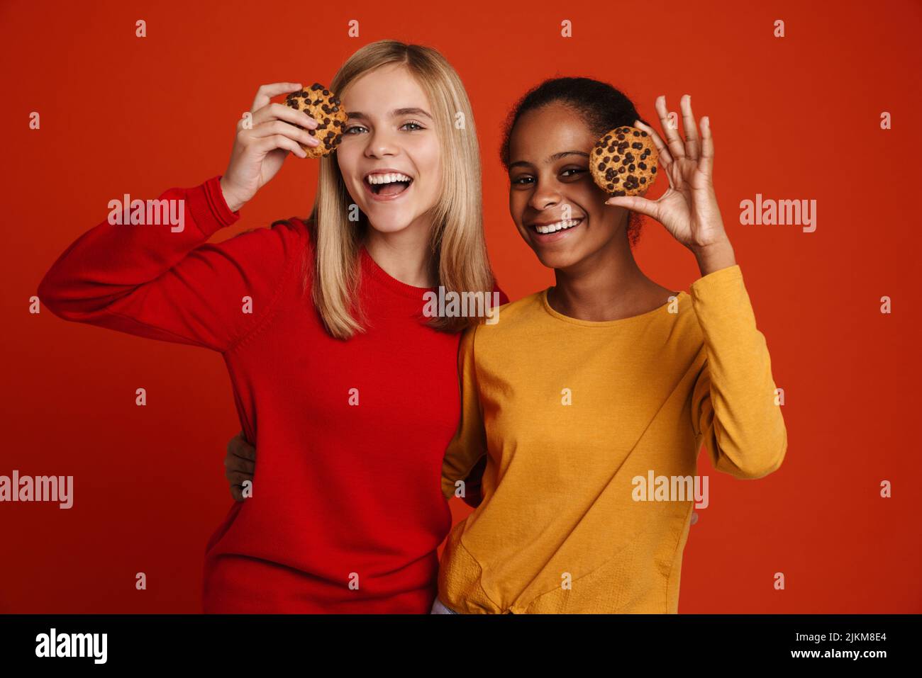 Multiracial two girls hugging while making fun with cookies isolated ...