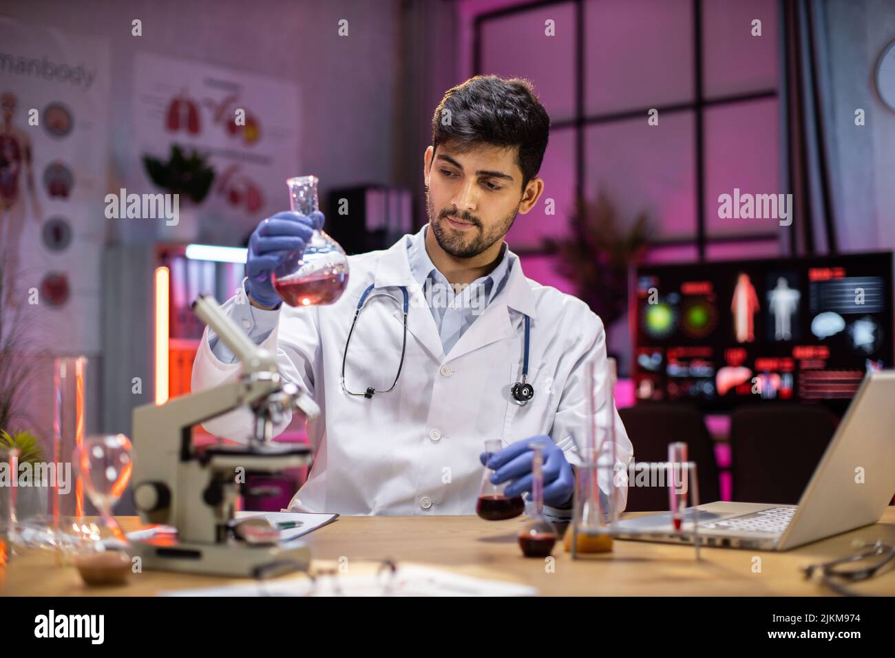 Yong indian male scientist working with test tubes wearing lab coat ...