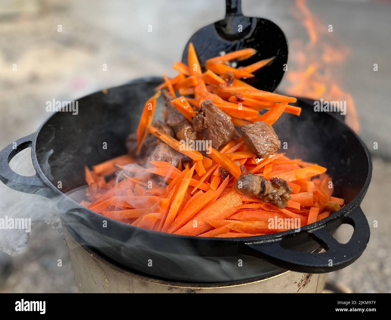 A closeup shot of the meat and carrot cooking process on the fire in a ...