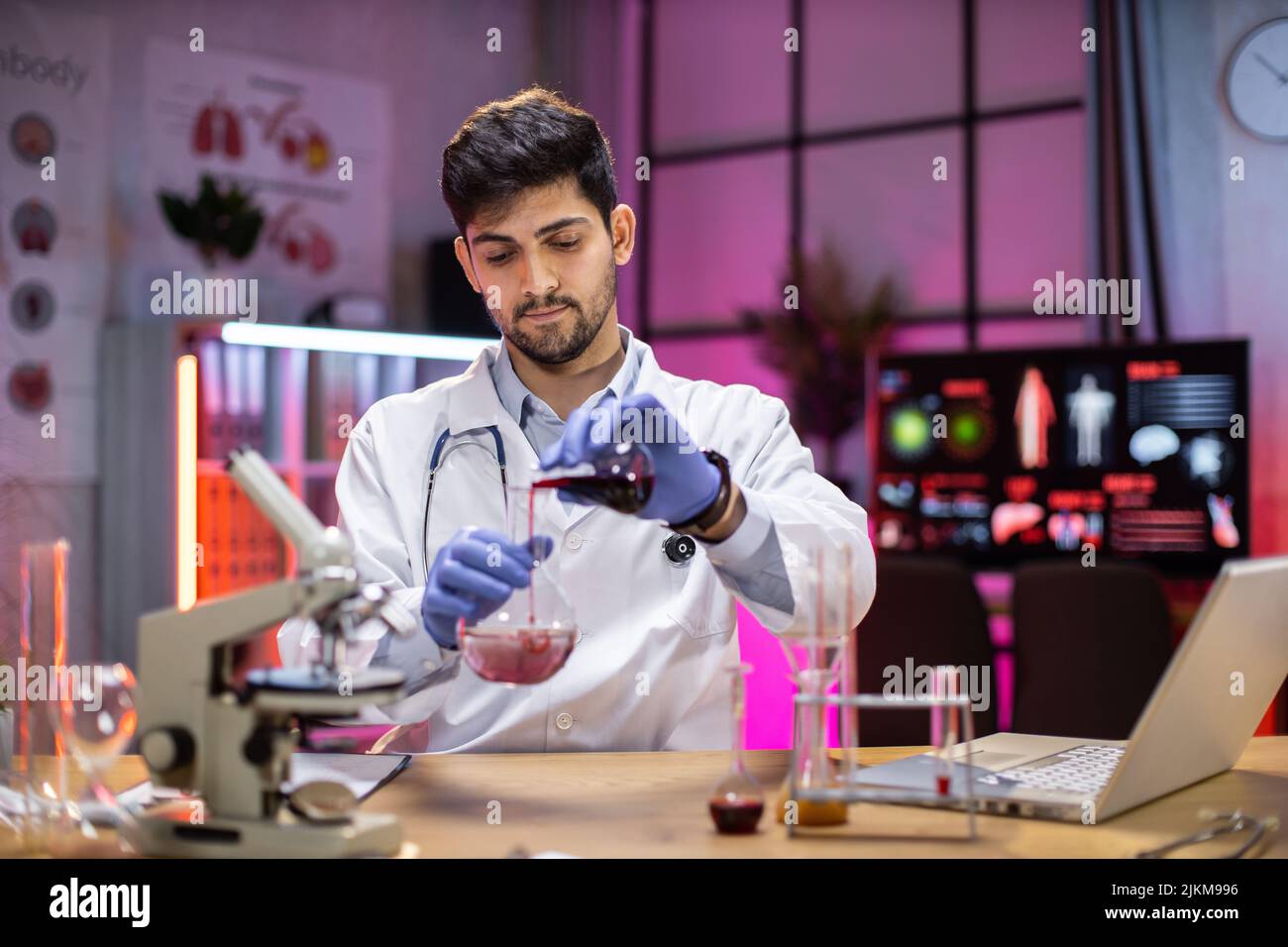 Yong indian male scientist working with test tubes wearing lab coat ...