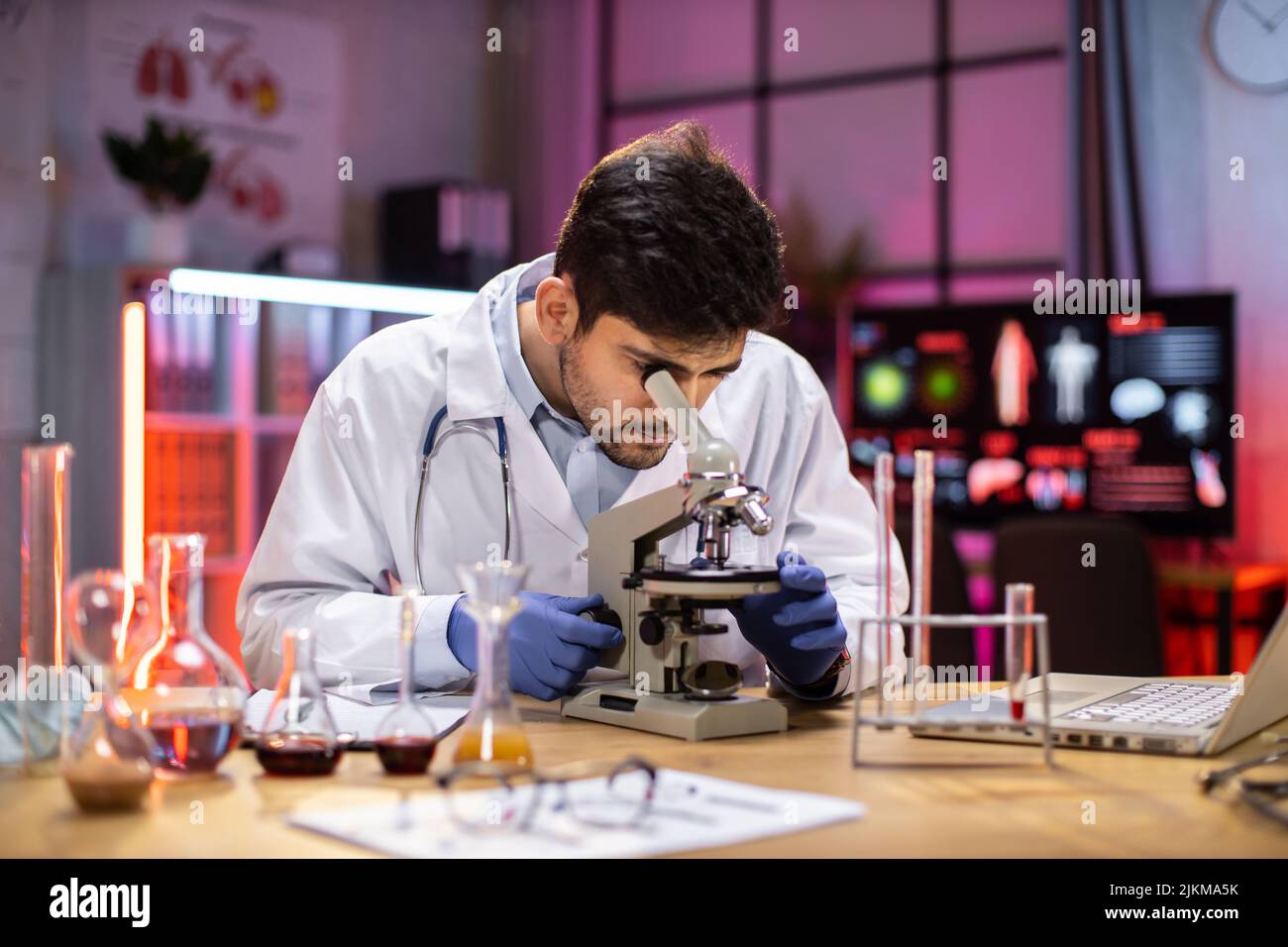 Young indian male researcher looking at the microscope analyze science ...