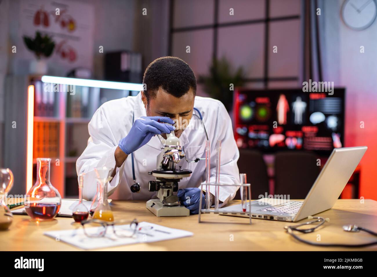 Young african american male researcher looking at the microscope analyze science, forensics ...