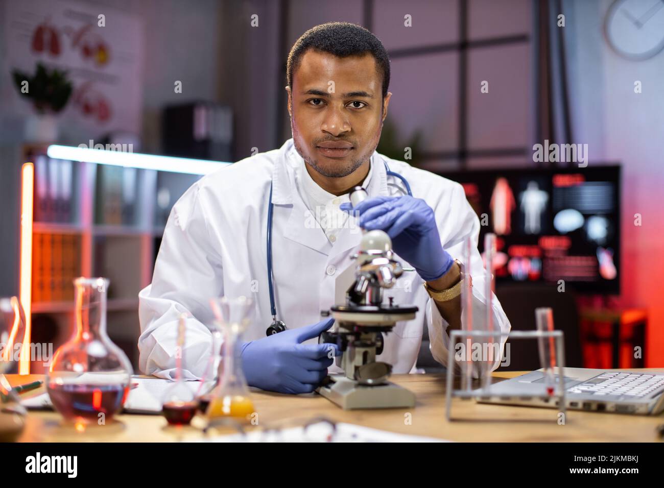 Modern medical research laboratory: portrait of scientist working, using microscope, analyzing ...