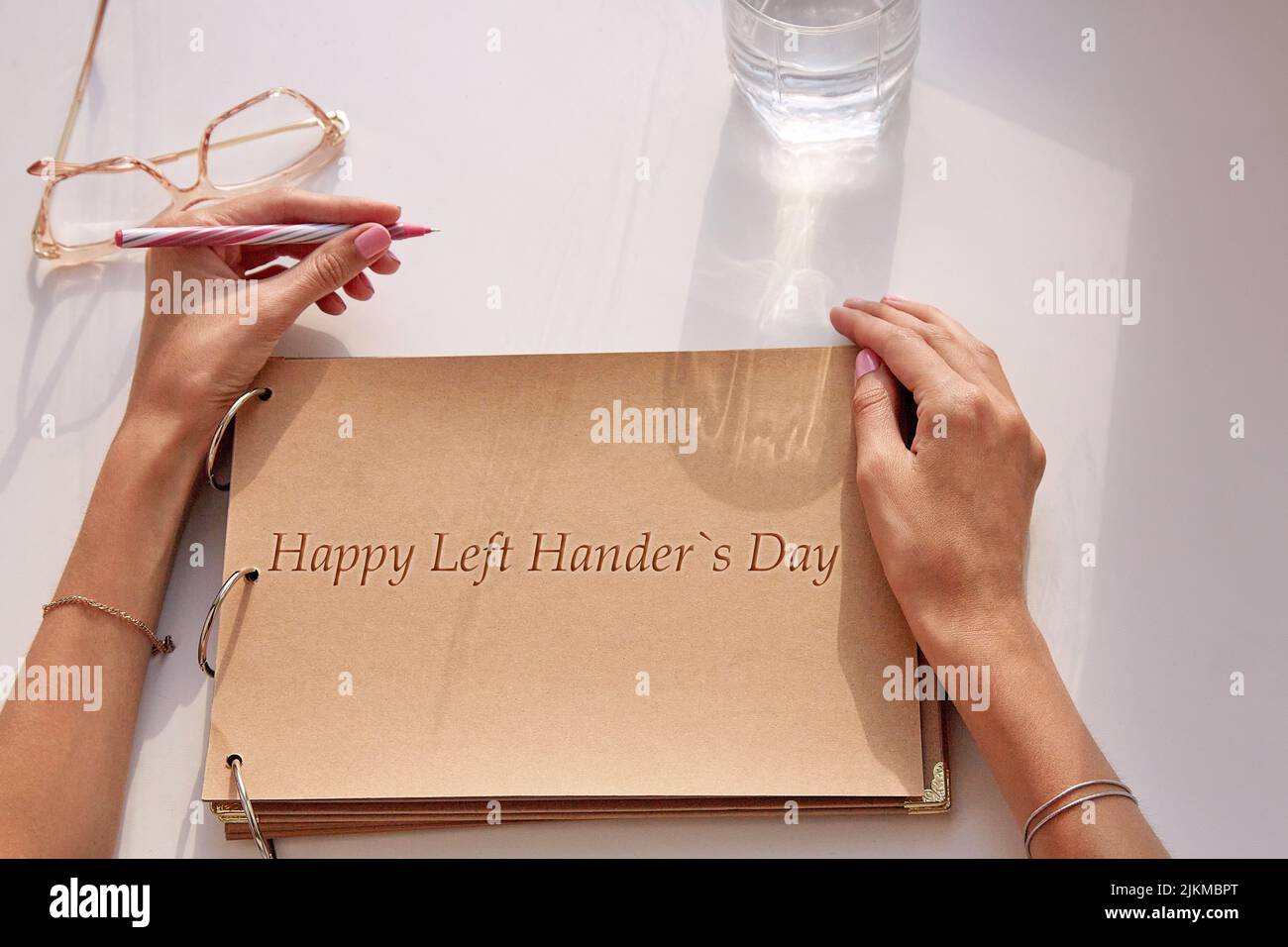 Woman is writing by her left hand on a craft paper album. Text Happy ...