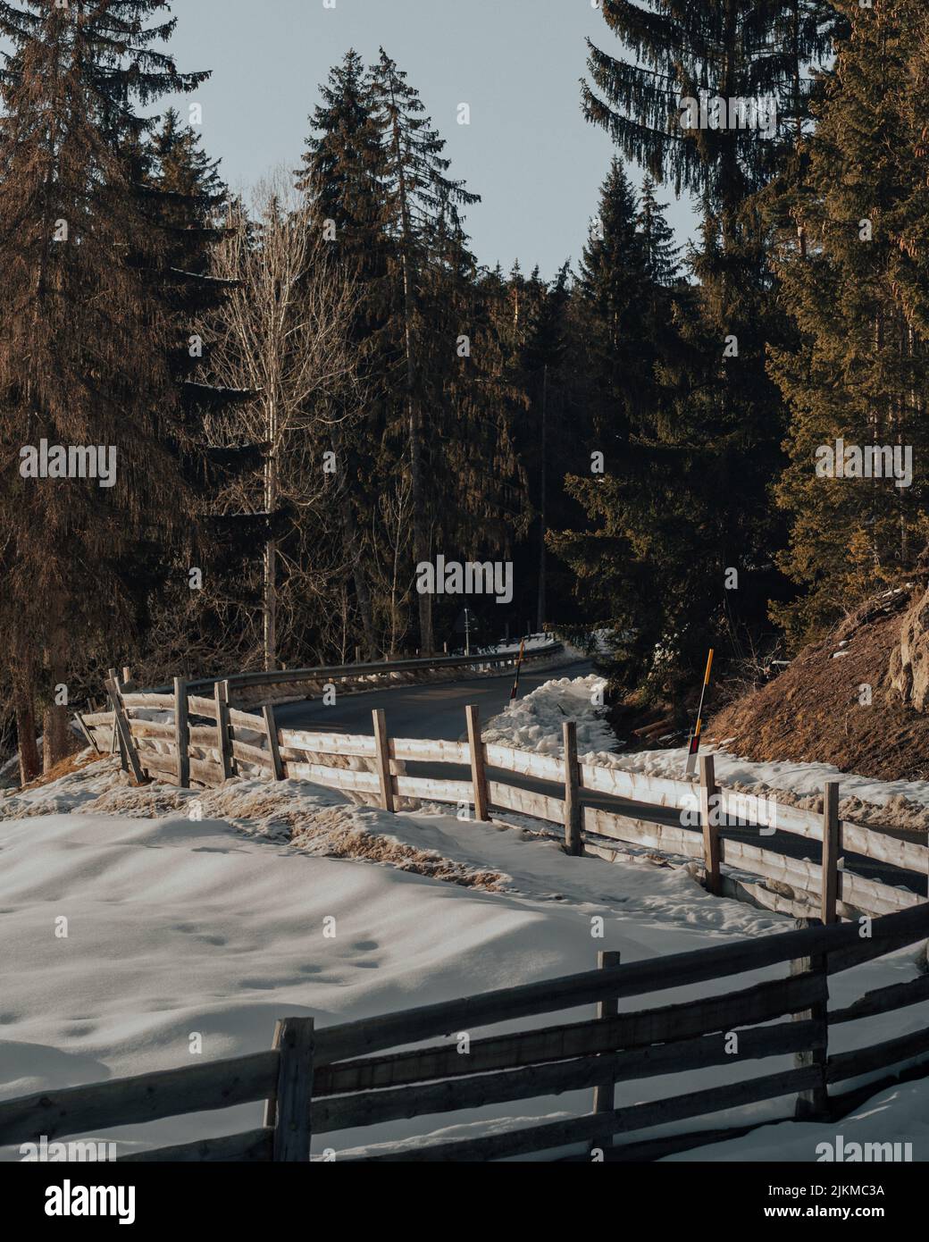 A winding road at the side of a mountain with wooden railing during ...