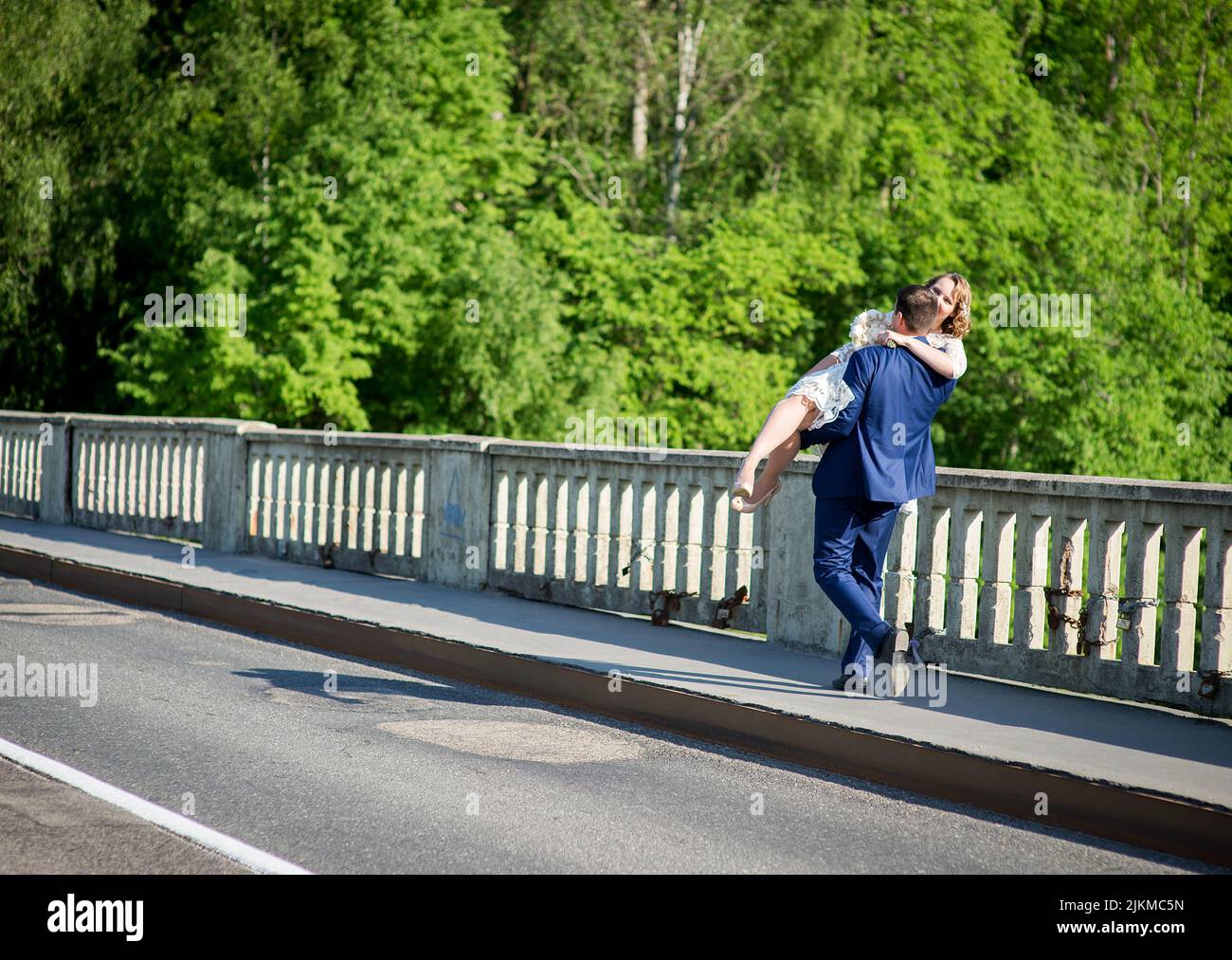 A view of the beautiful couple- the groom carrying the bride in his ...