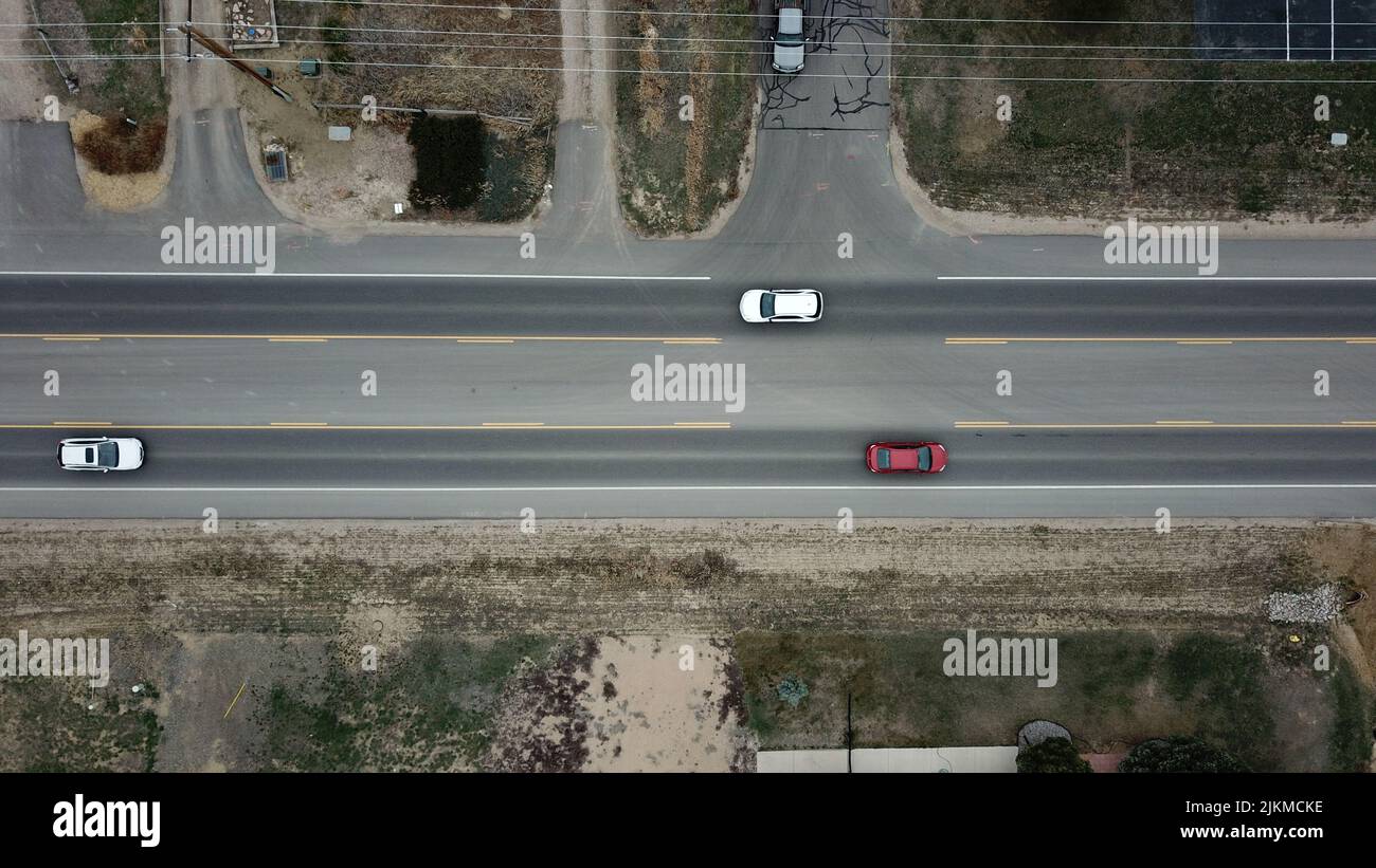 An aerial top view of cars driving on the asphalt road surrounded by ...