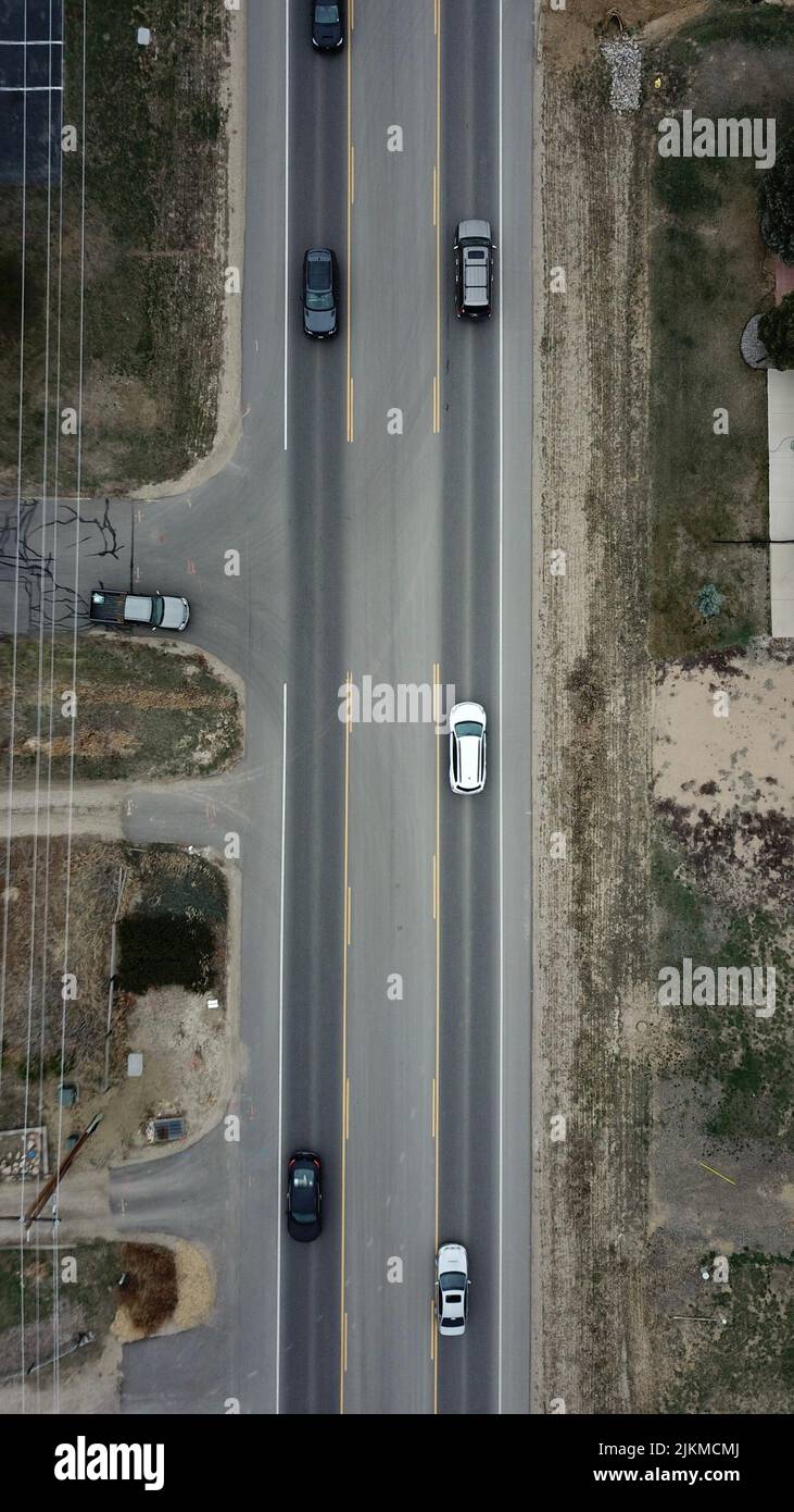 An aerial top view of cars driving on the asphalt road surrounded by ...