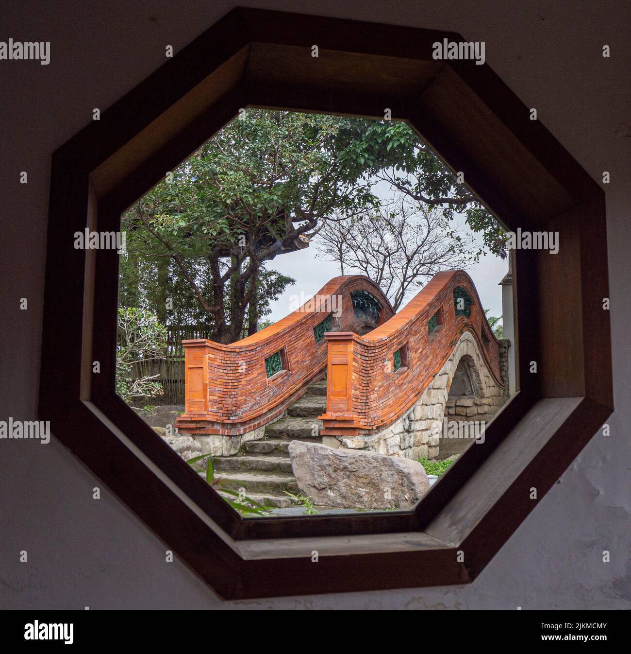 A fancy brick arch bridge at an oriental park as seen through an ...