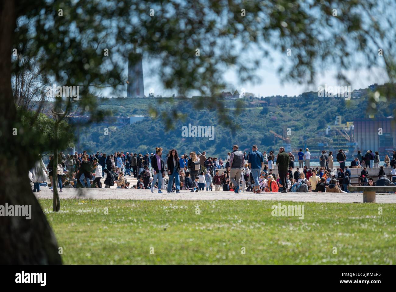 A large crowd of people enjoying the sunny weather near the water in ...
