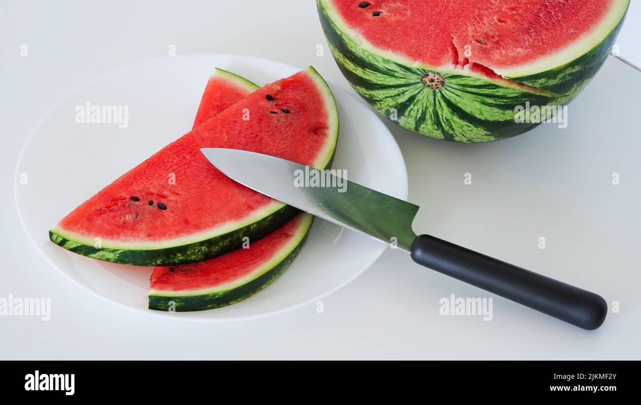 Close-up slices of fresh ripe red watermelon on a plate with a knife on ...