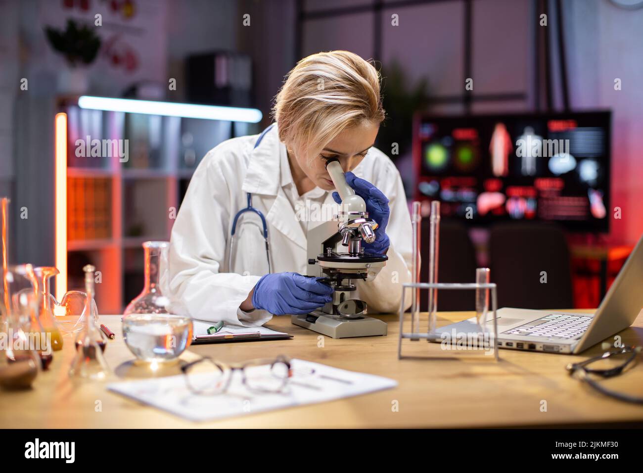 Young female researcher looking at the microscope in the life science ...