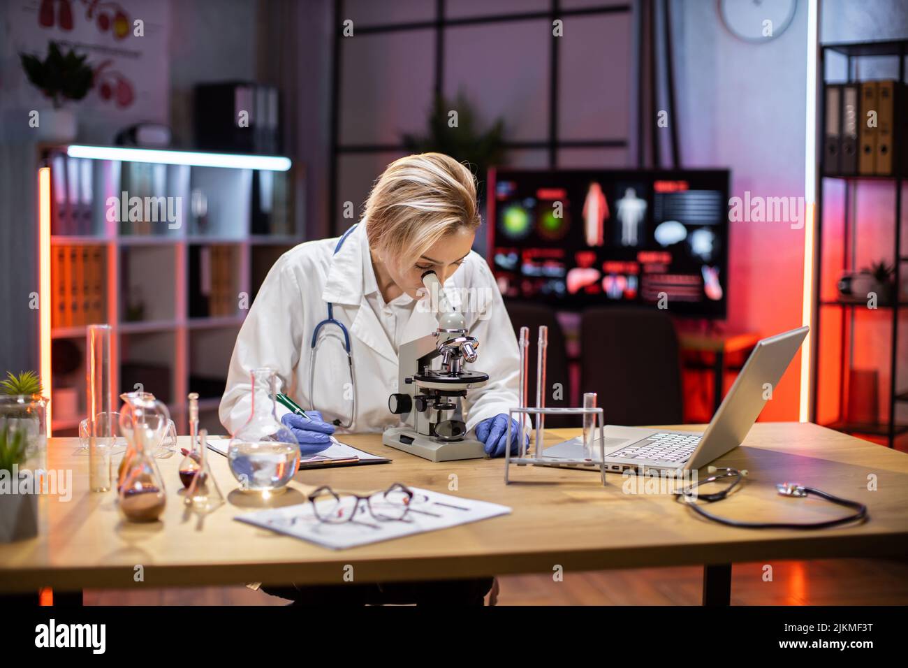Young female researcher looking at the microscope in the life science ...