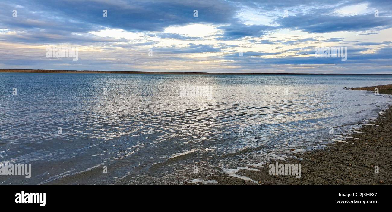A peaceful scenery of the azure sea washing the sandy coast at sunrise ...
