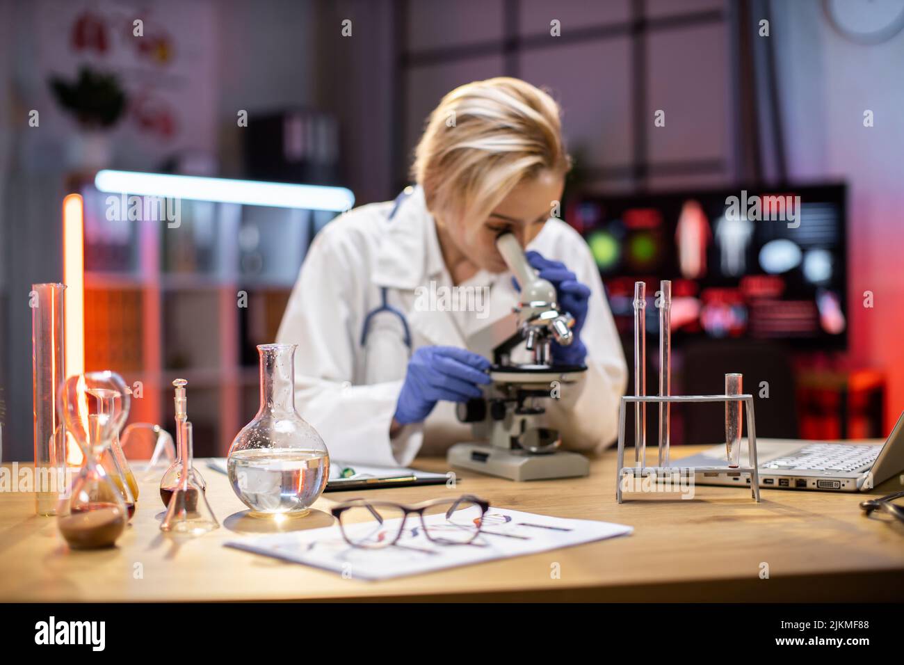 Young female researcher looking at the microscope in the life science ...