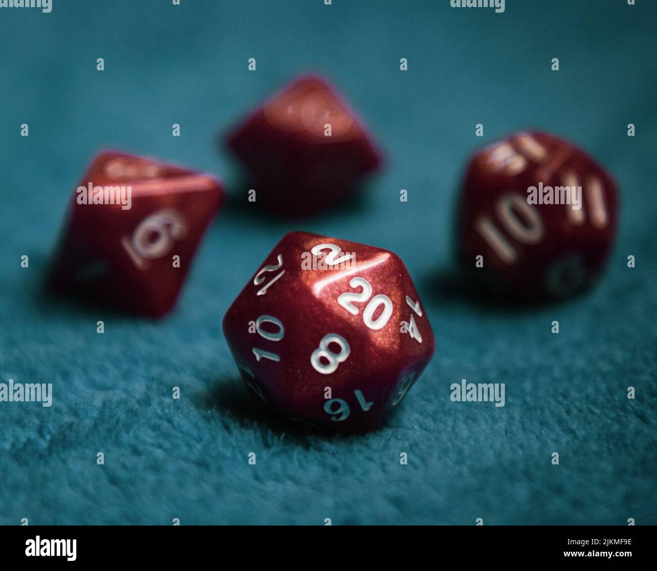 A selective focus of a set of red dice with numbers, on a blue fabric ...