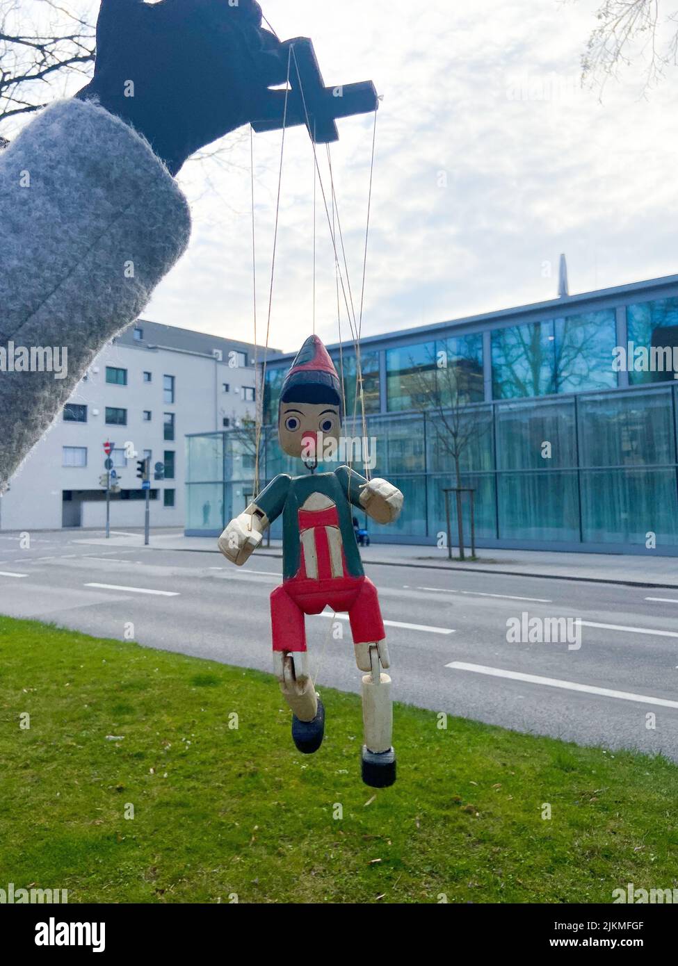 A vertical shot of a colorful wooden marionette outdoors and a hand ...