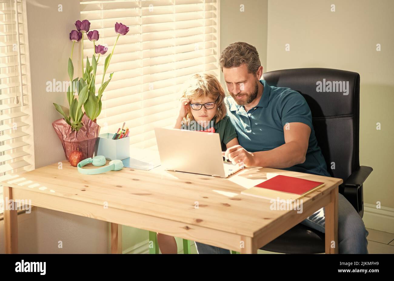 happy father helping his school son study with laptop at home ...