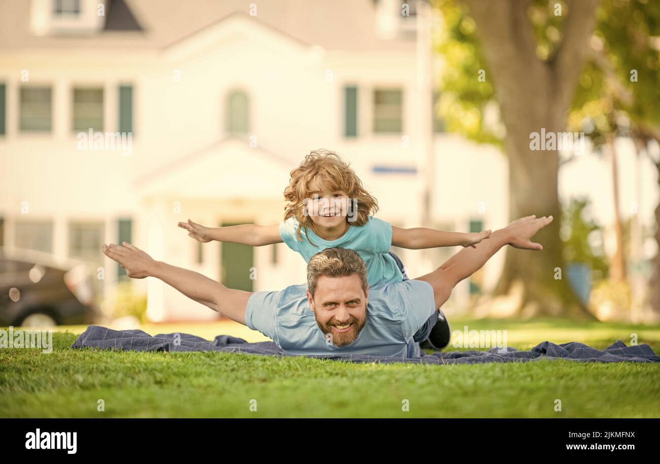glad father with son relax together on green park grass, parenting ...