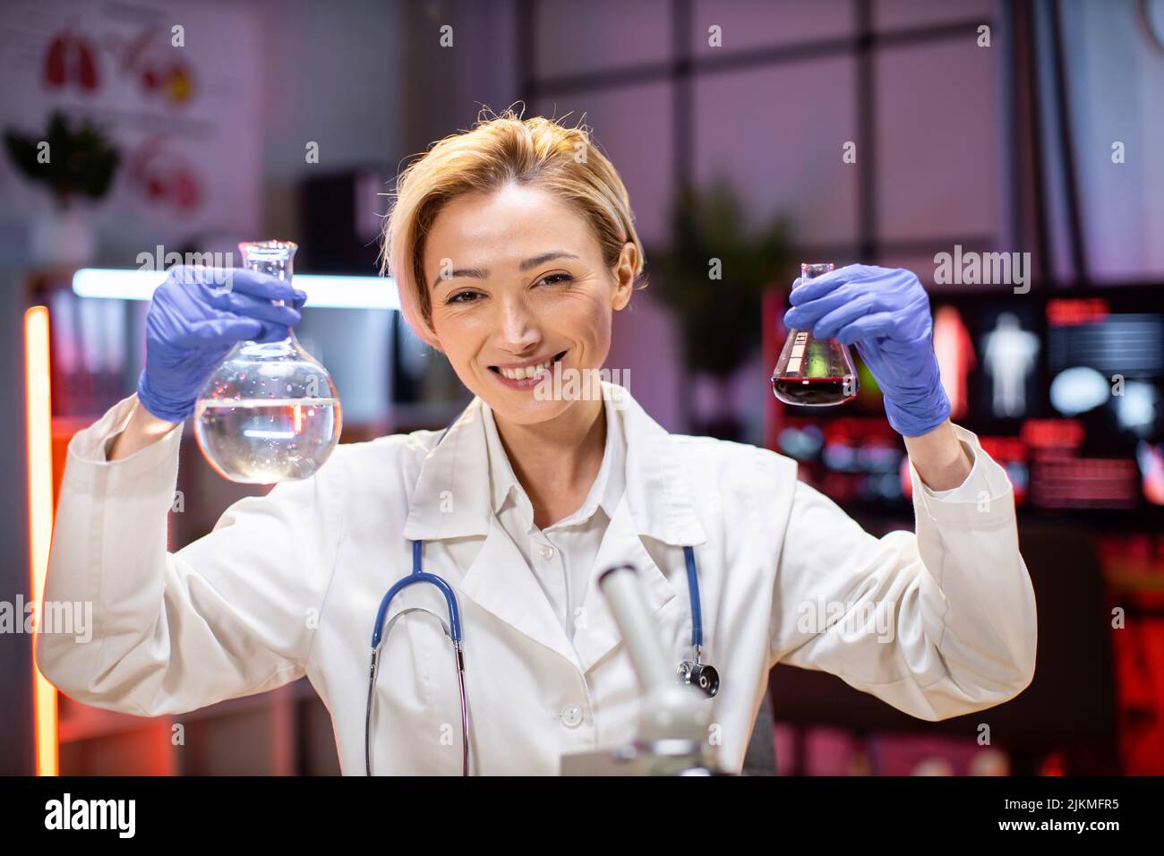 Positive female scientist or medical in lab coat holding test tube with ...