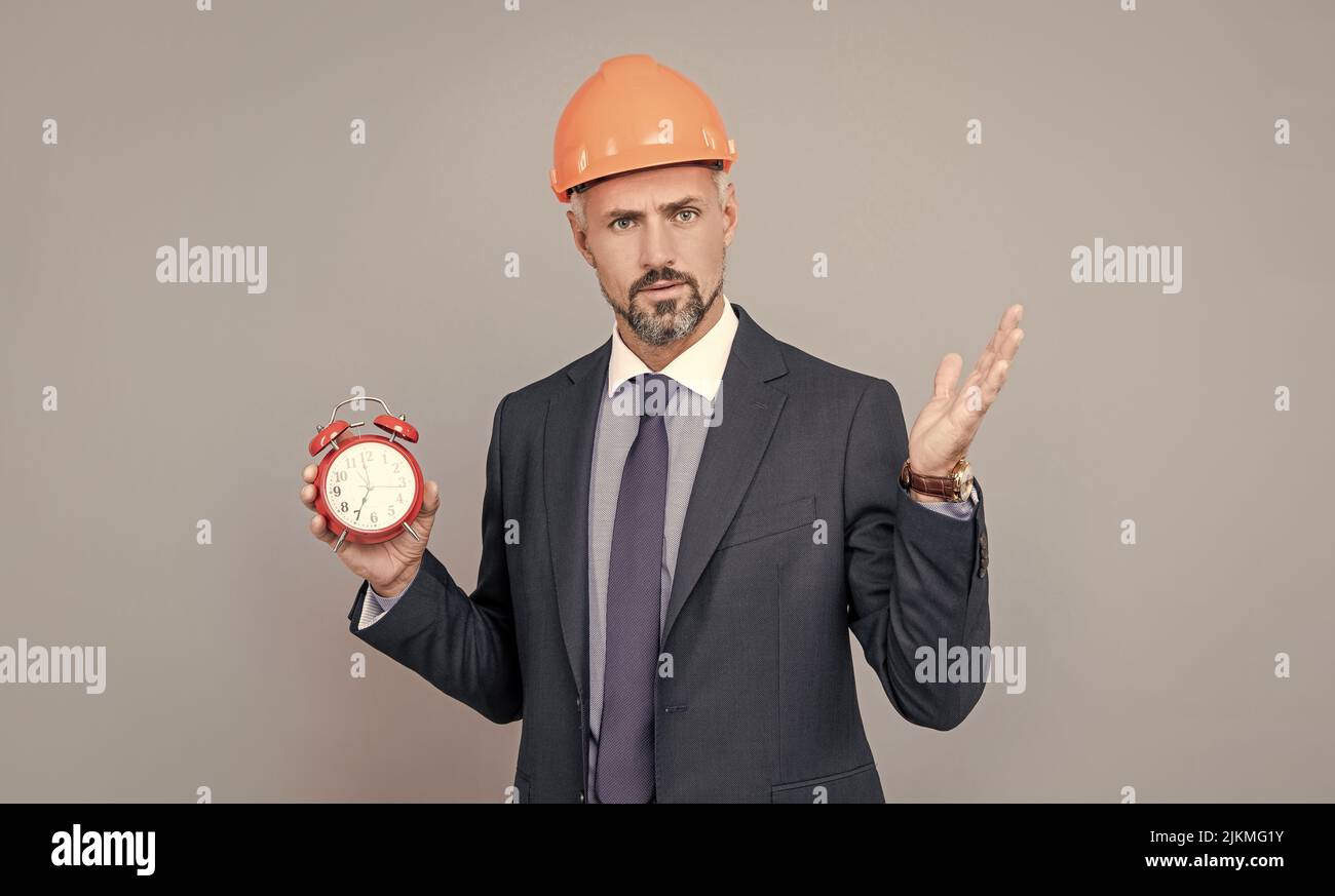 architect man in businesslike suit and hardhat holding alarm clock ...