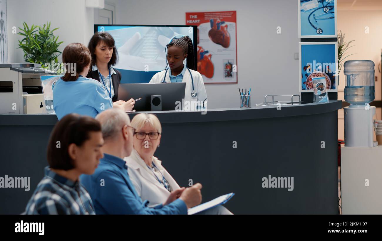 Female employee working at hospital reception counter to give ...