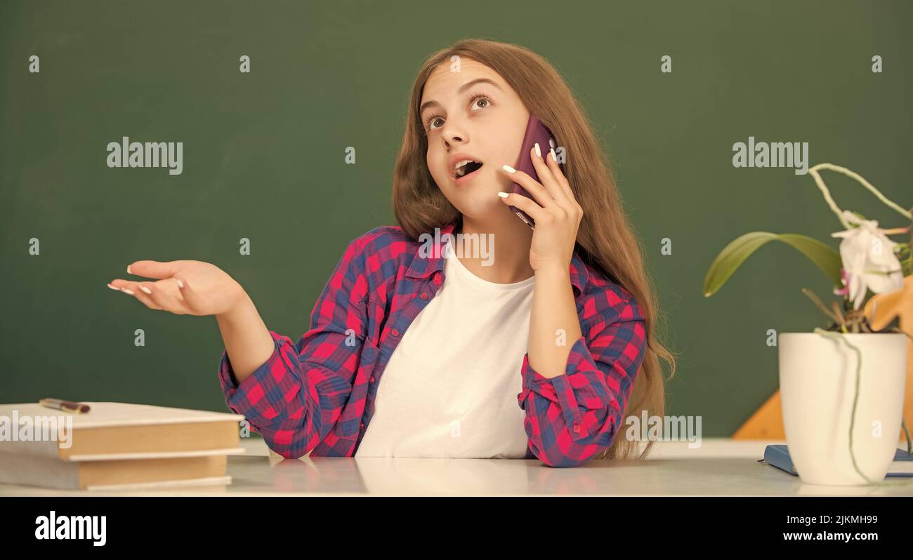 dreamy child at school talking on phone on blackboard background ...