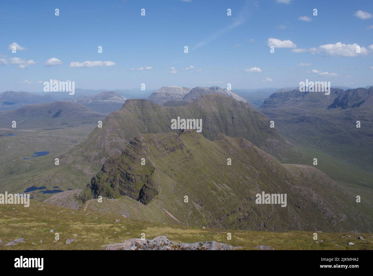 A gorgeous view of green fields and steep hills under a bright blue sky ...