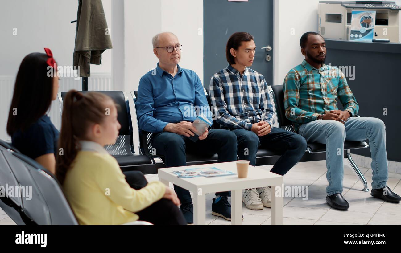 Diverse group of people sitting together in hospital waiting room ...