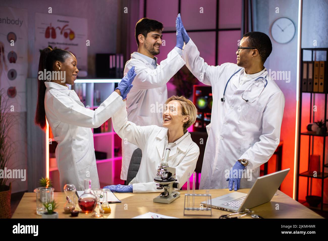 Professional international medical scientists giving high five after ending of the experiment in ...