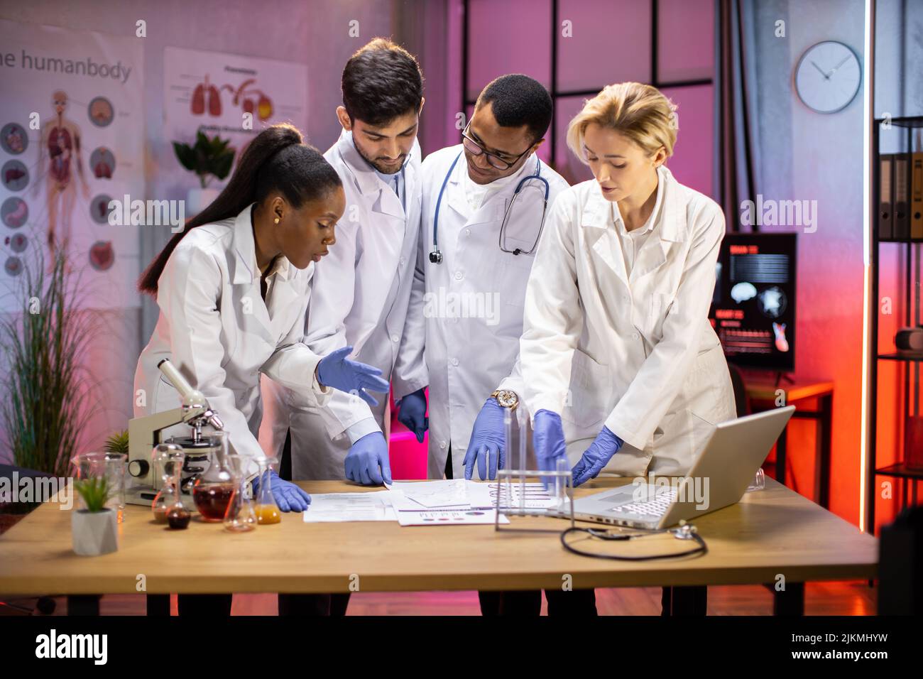 Diverse team of medical scientists solve problems and point looking at results of research ...