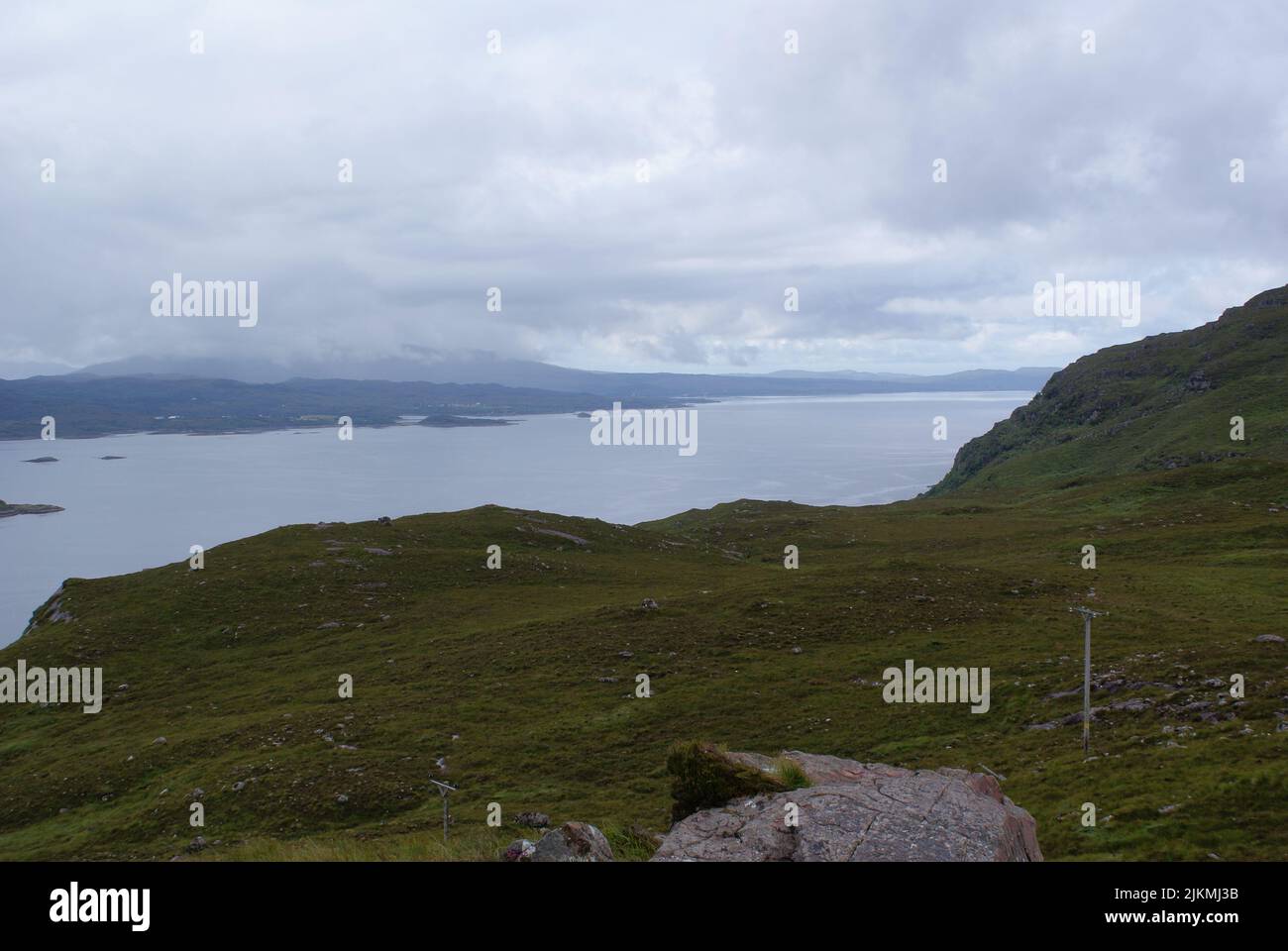 A scenic view of grassy terrain with electric posts under a gloomy sky ...