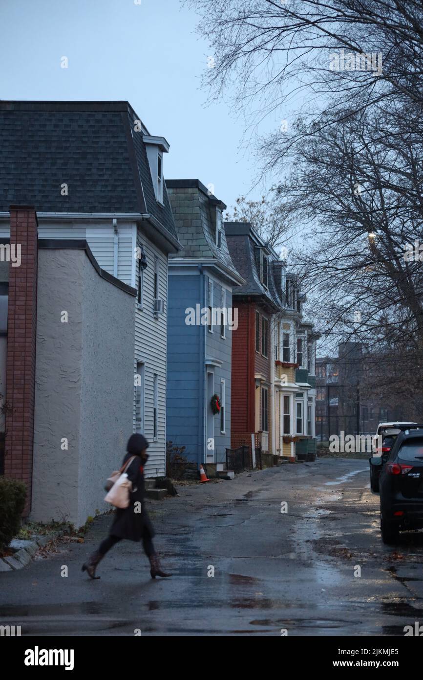 A lady crossing a street in front of colorful houses Stock Photo - Alamy