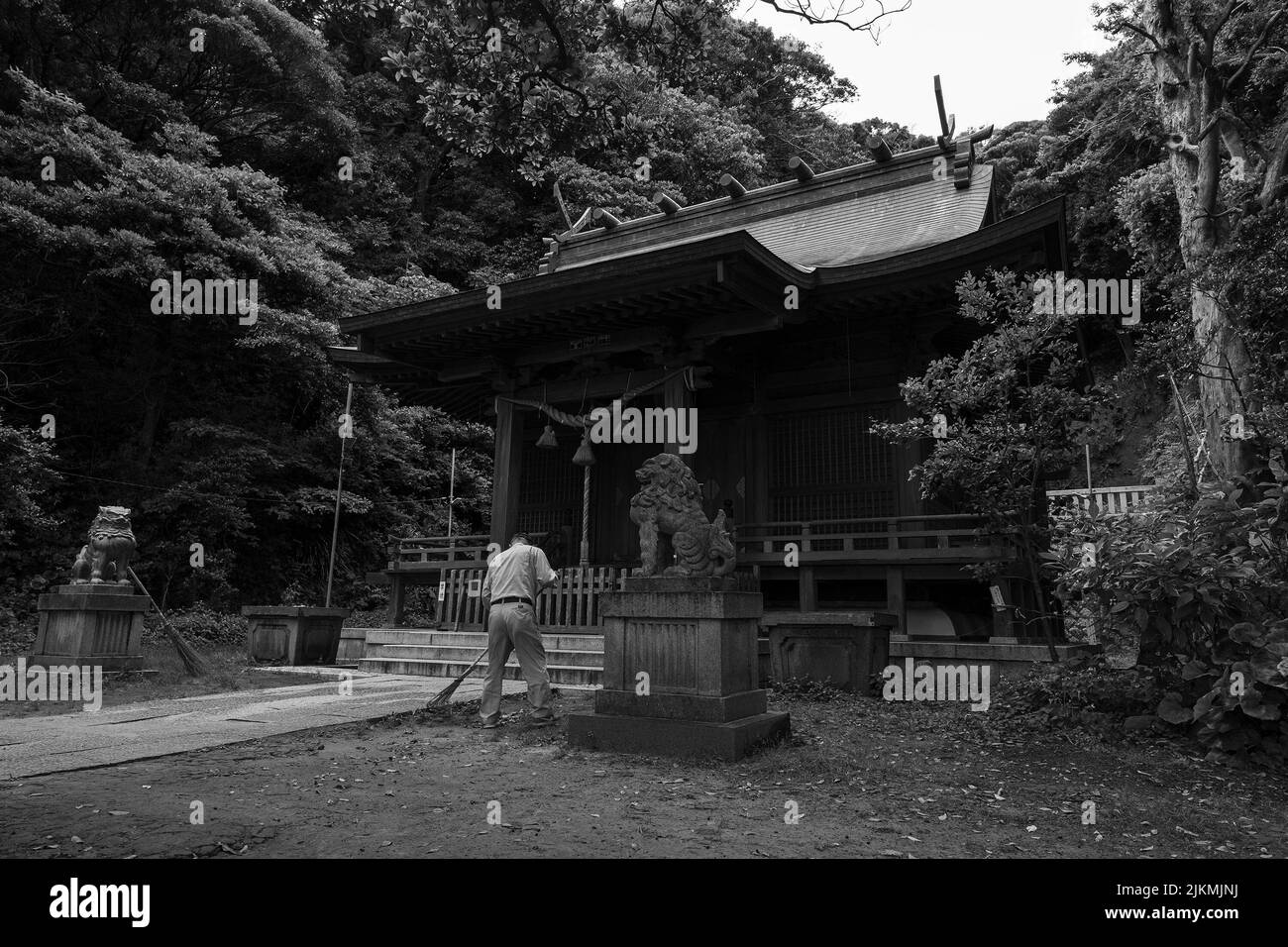 An old, Japanese man cleaning the floor of a temple with a broomstick ...