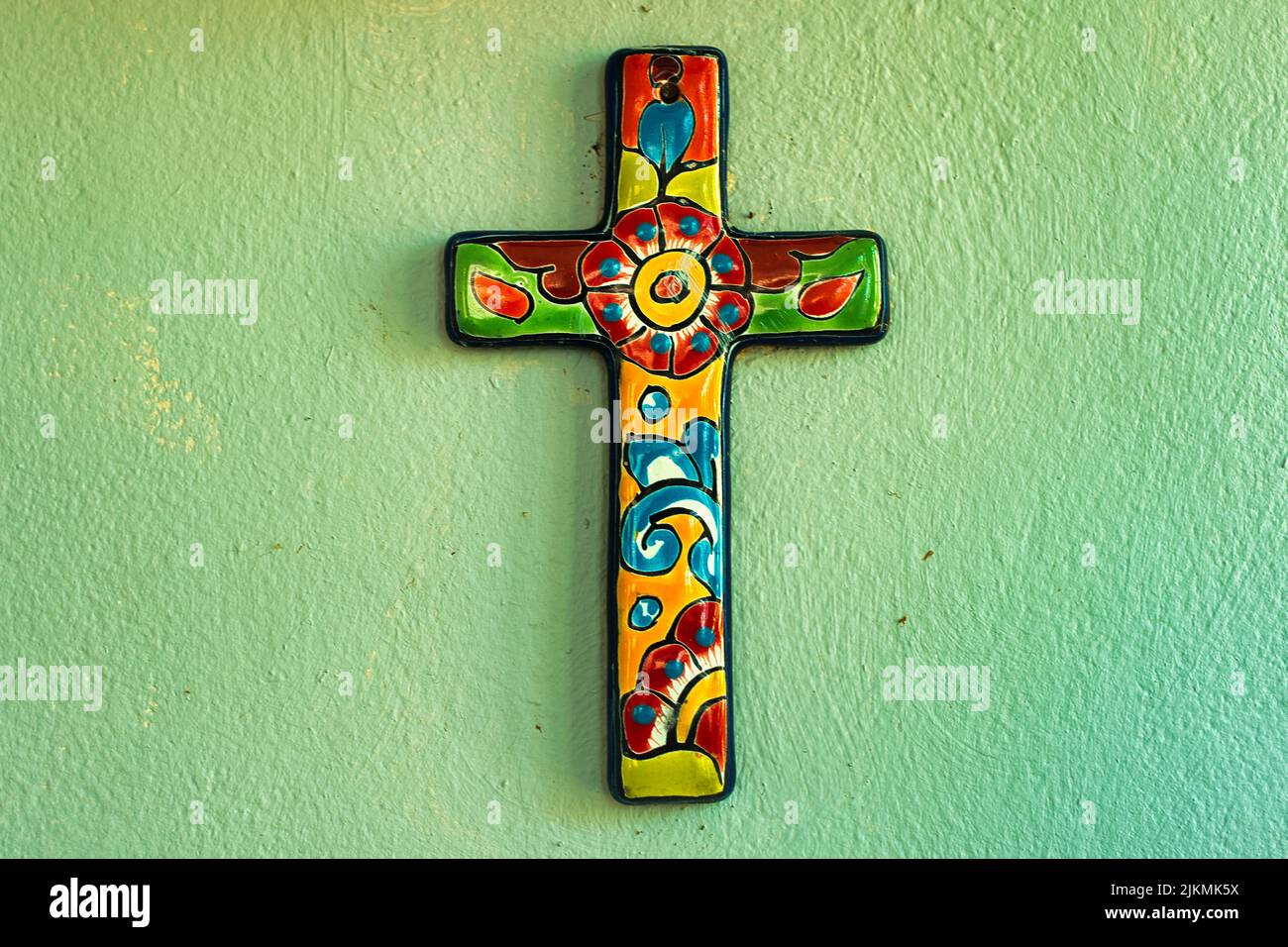 A colorful cross with a vibrant pattern isolated on a green background ...