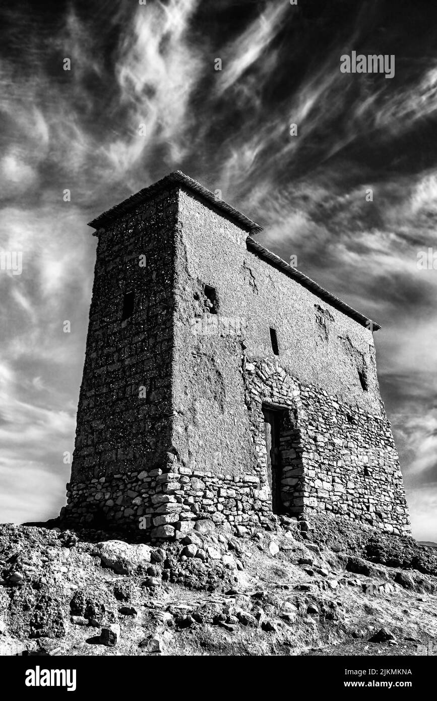 A vertical grayscale shot of an old brick building with weathered walls ...