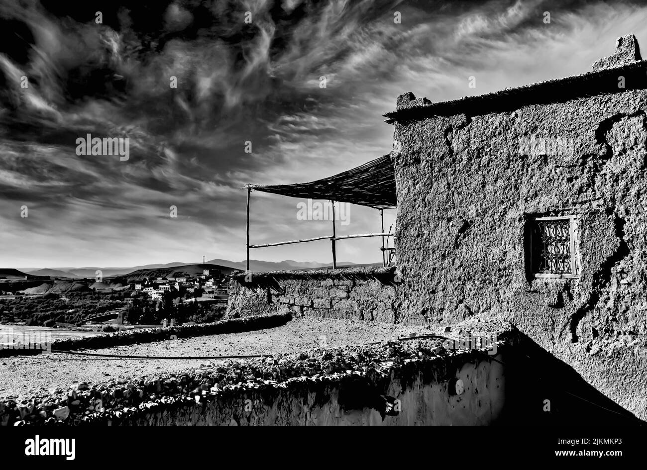 A grayscale shot of small houses under a bright cloudy sky in Morocco ...